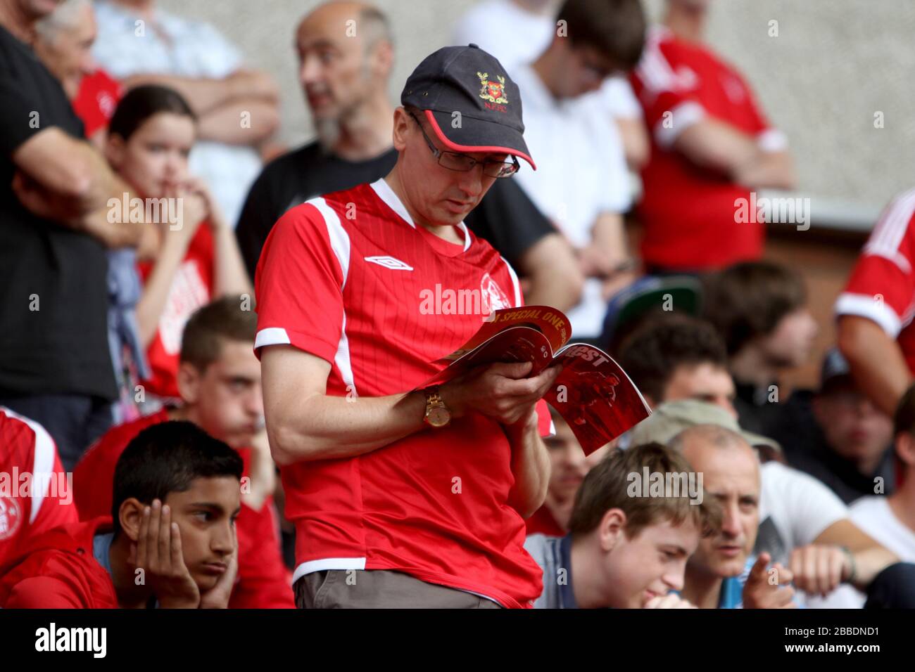 A fan reads the matchday programme Stock Photo - Alamy