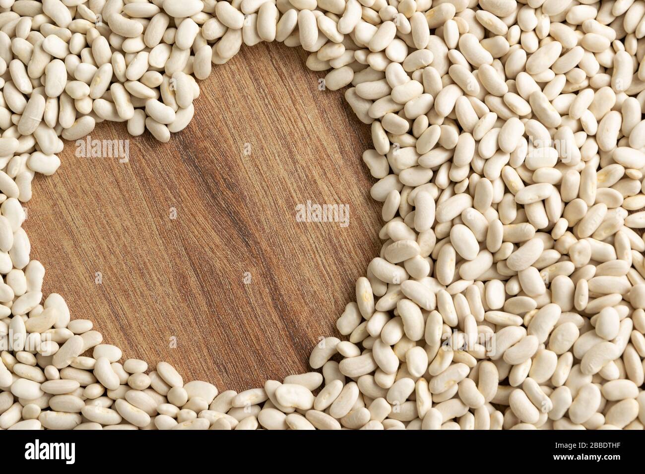 White raw aw beans background with wooden heart shape for space for text. Natural protein legume ...