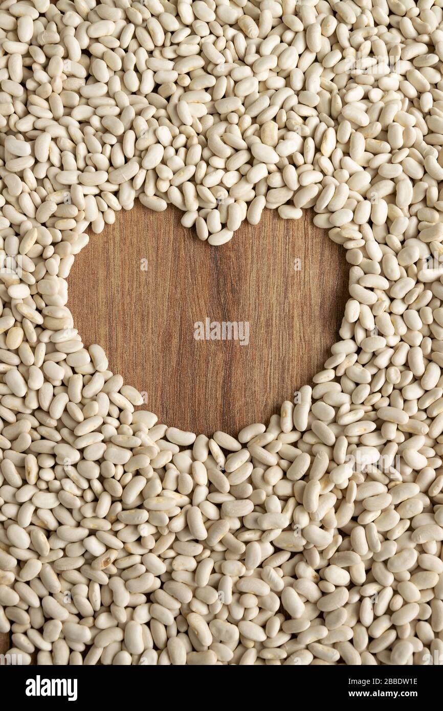 White raw aw beans background with wooden heart shape for space for ...