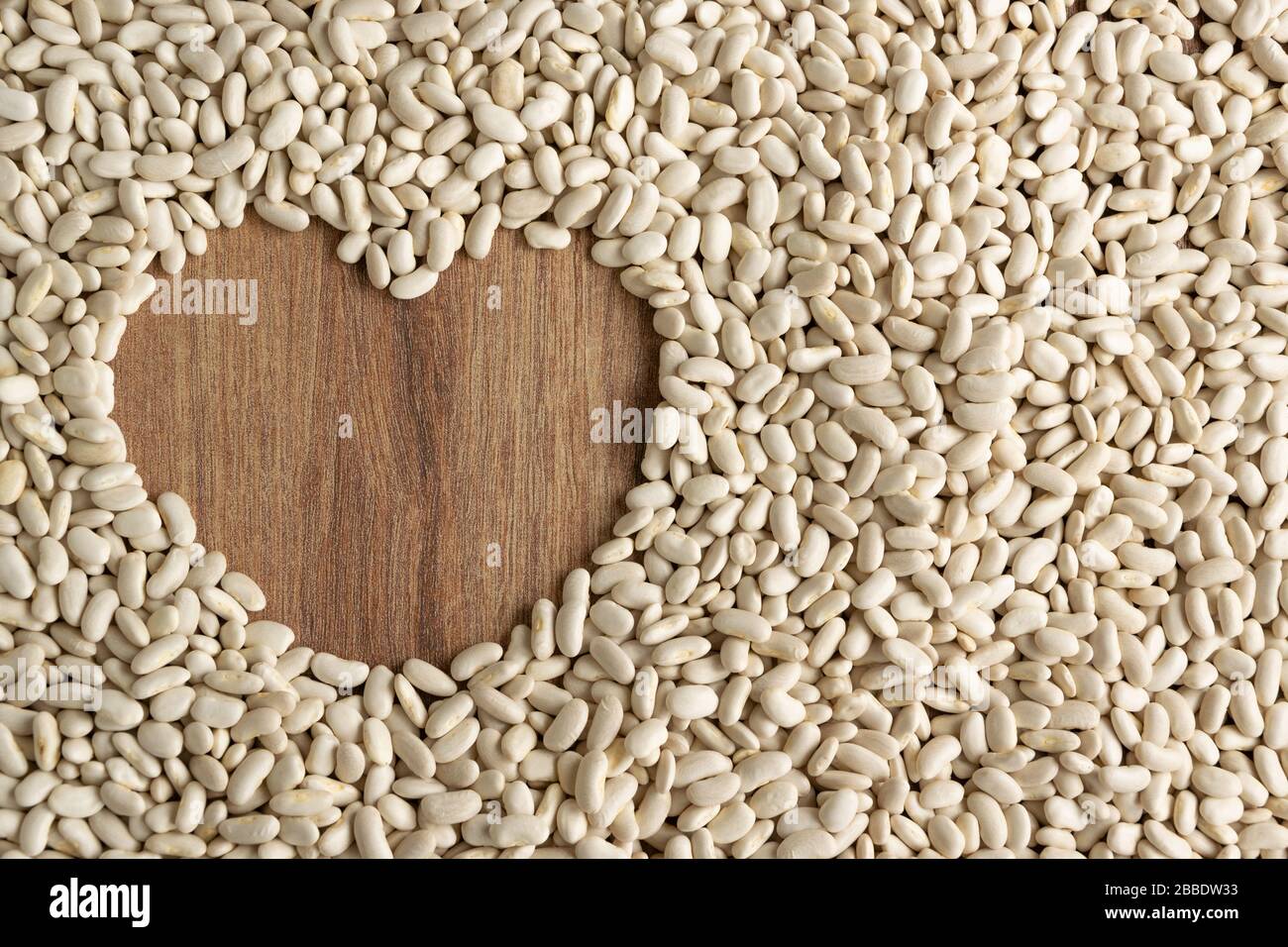White raw aw beans background with wooden heart shape for space for ...