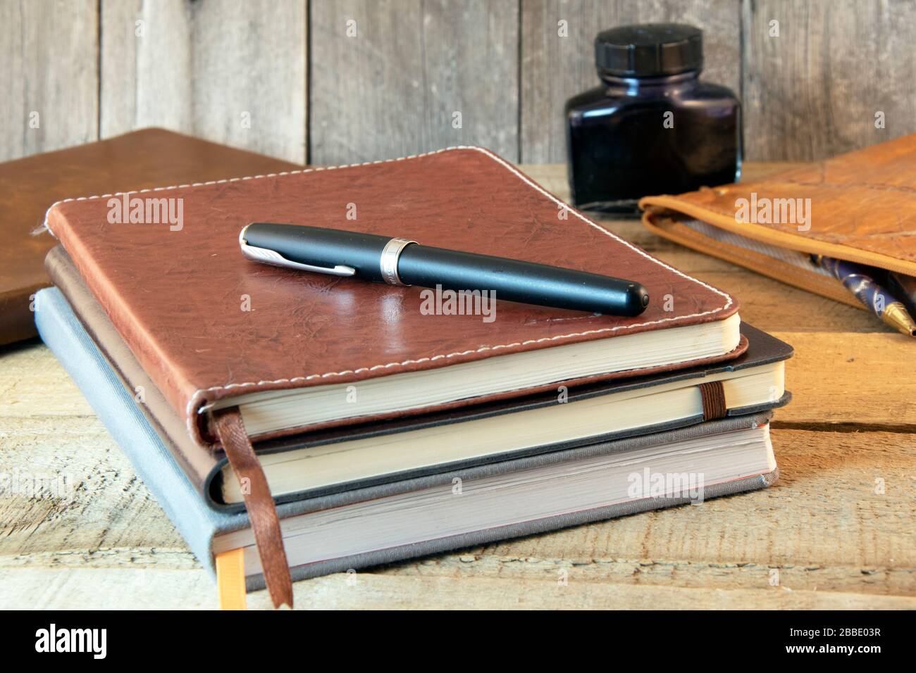 Pile of notebooks, pen, ink with wooden background Stock Photo - Alamy