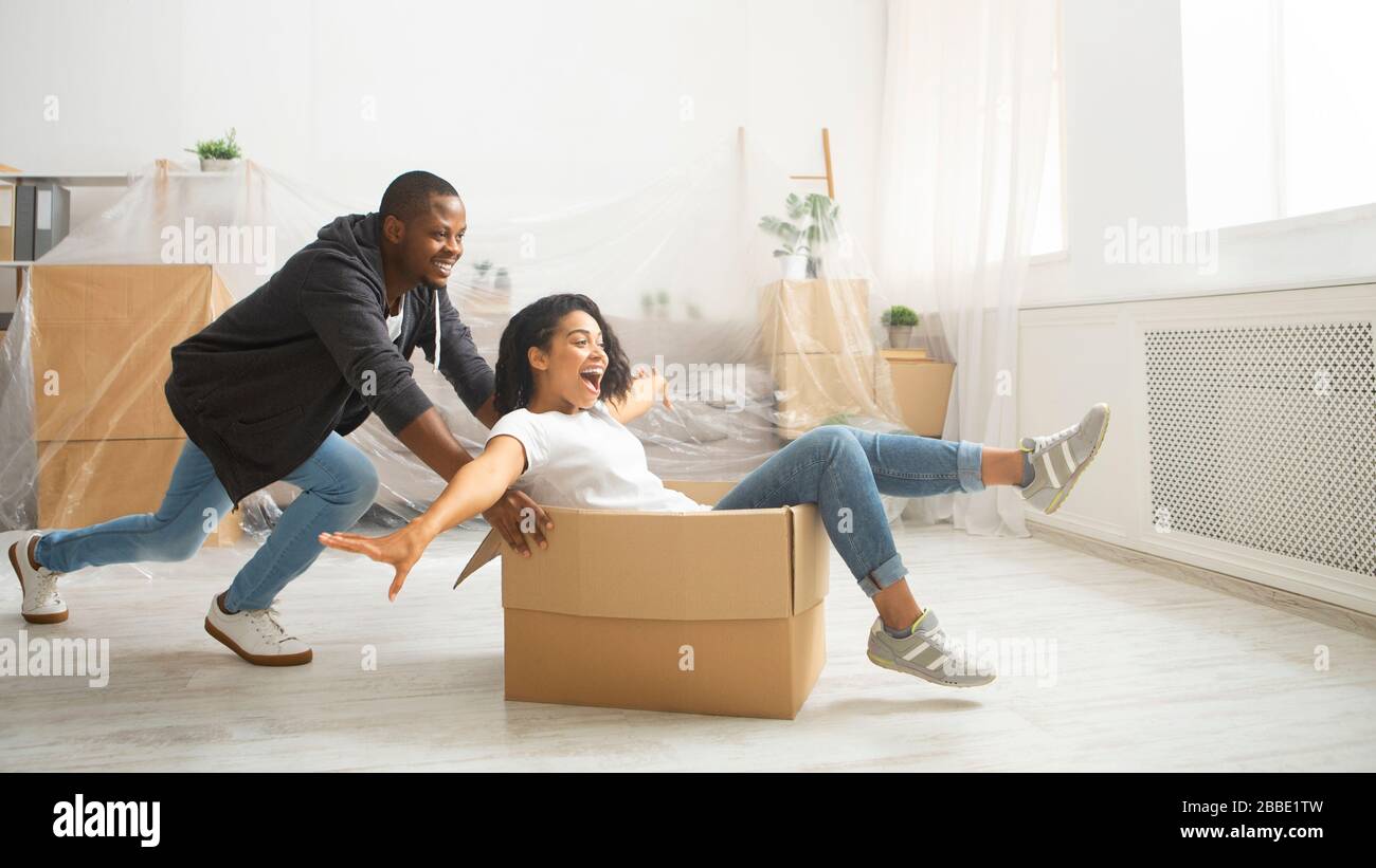 African american husband rolling his wife in cardboard box Stock Photo ...