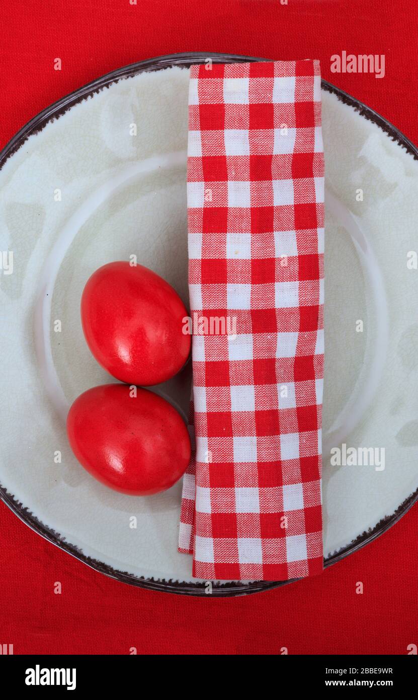 Easter table, place setting. Red eggs and napkin on a plate, red ...