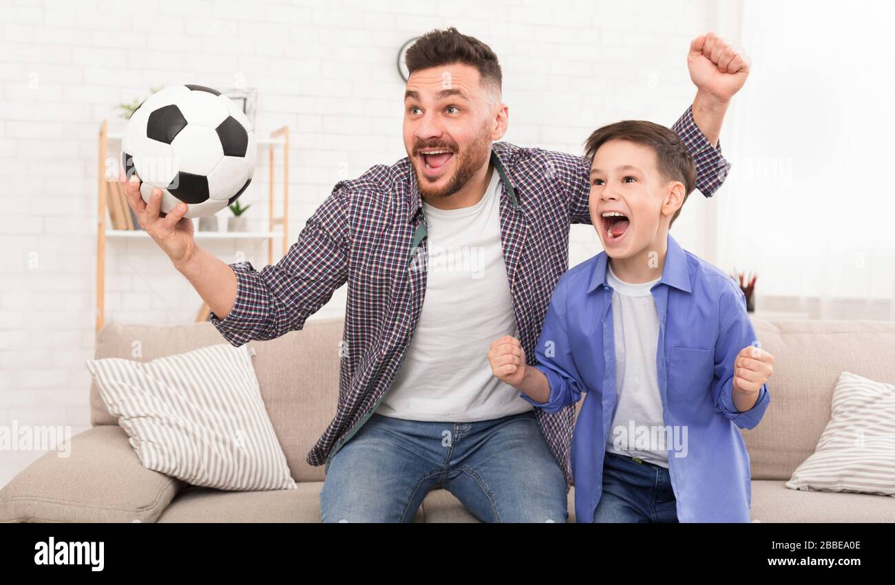 Emotional dad and son with football ball watching sport on tve Stock ...