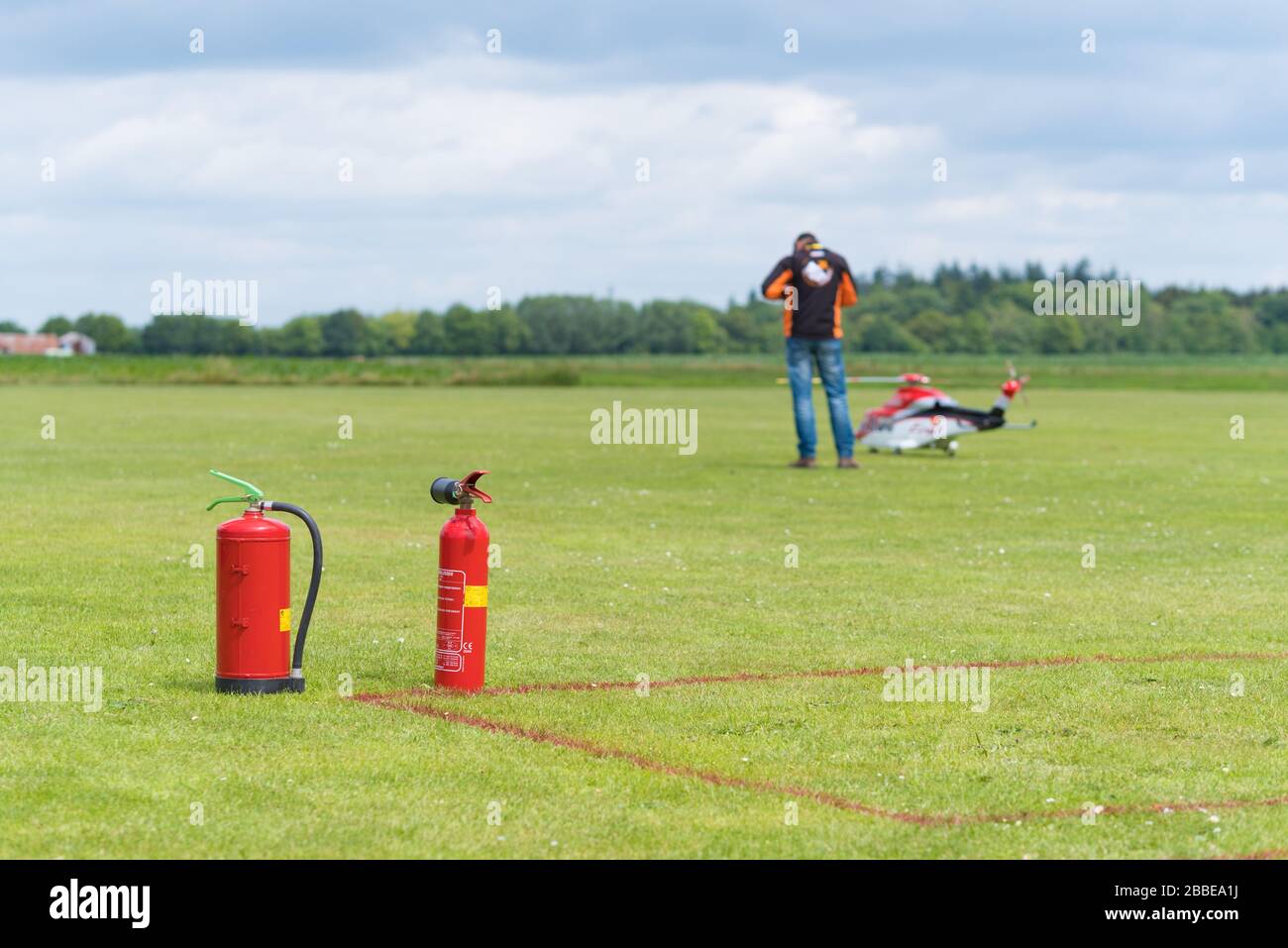 two fire extinguishers while a man in the background is busy with its ...