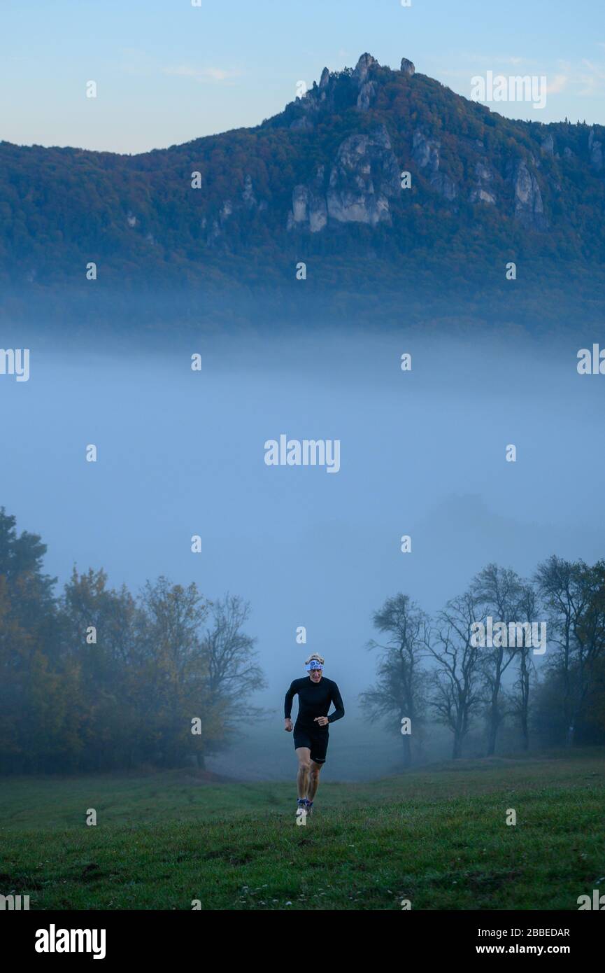 Active young man, runner train in misty autumn nature. Grey color tone ...