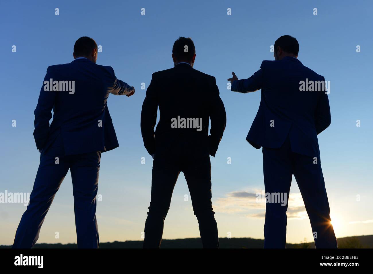 Silhouettes of company leaders standing on sunset sky background. Board ...