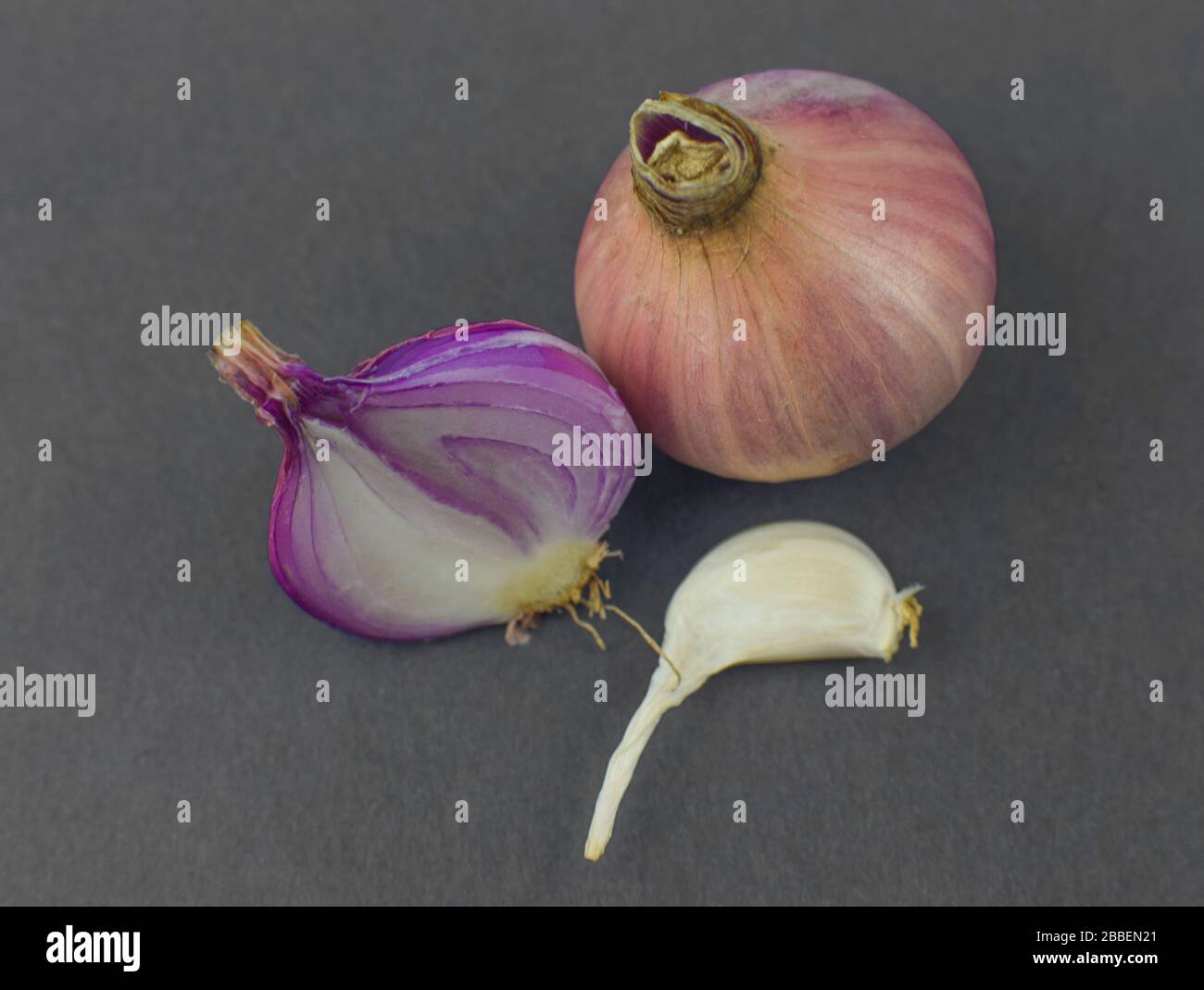 A half peeled pink colored onion placed beside a medium sized unpeeled ...