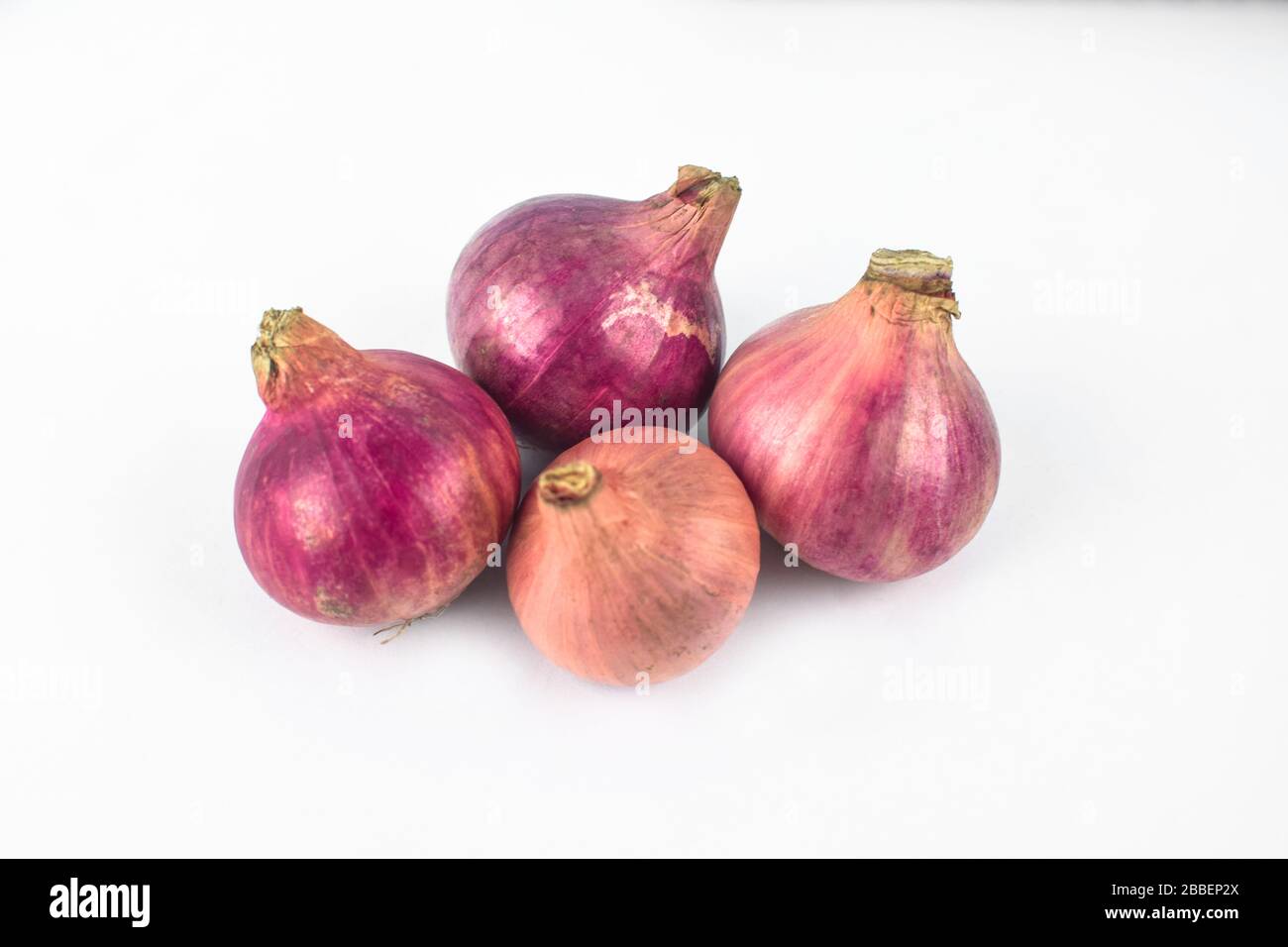 Four medium size fresh and ripe red onion isolated on a bright white ...