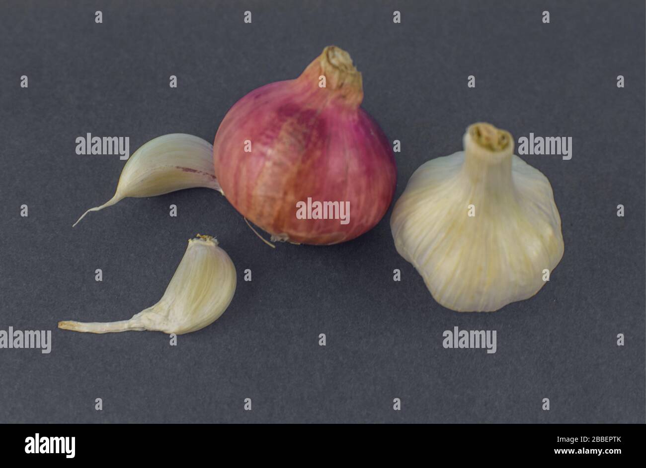Pink colored medium size onion and a white garlic beside some garlic ...