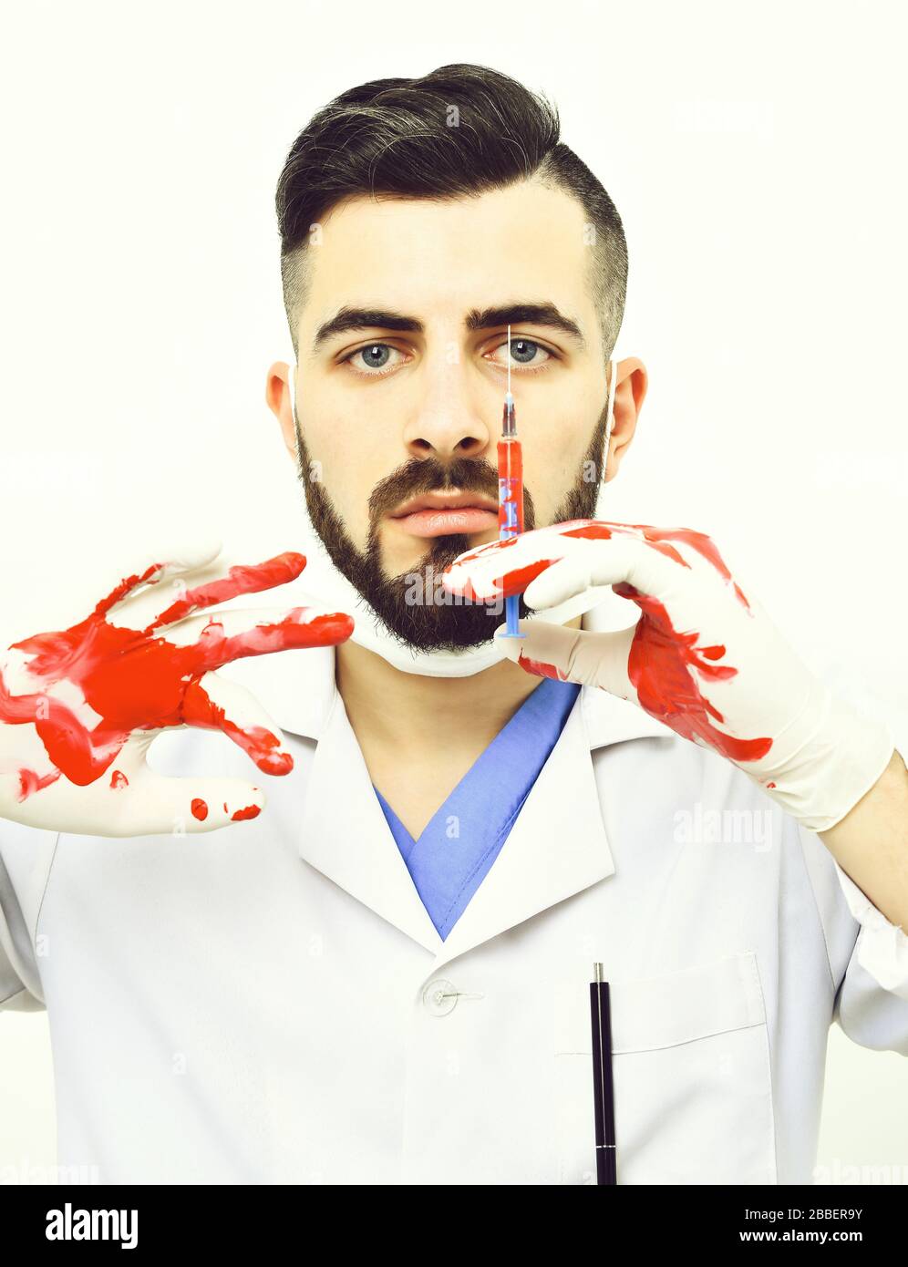 Doctor with serious face expression and dark beard holds syringe in ...
