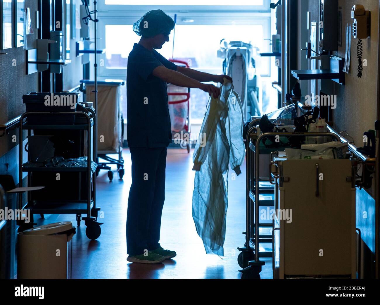 Schwerin, Germany. 26th Mar, 2020. A nurse puts on her protective ...