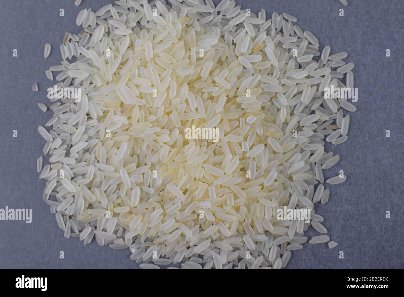 Stack of white fresh rice grains gathered together in front on a light ...