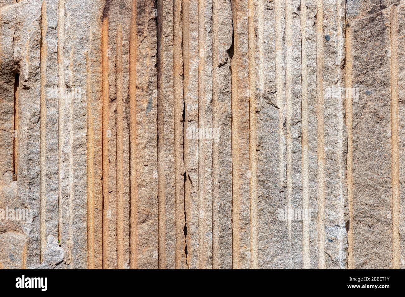 A series of vertical lines in a cliff face in a rock quarry. The lines ...