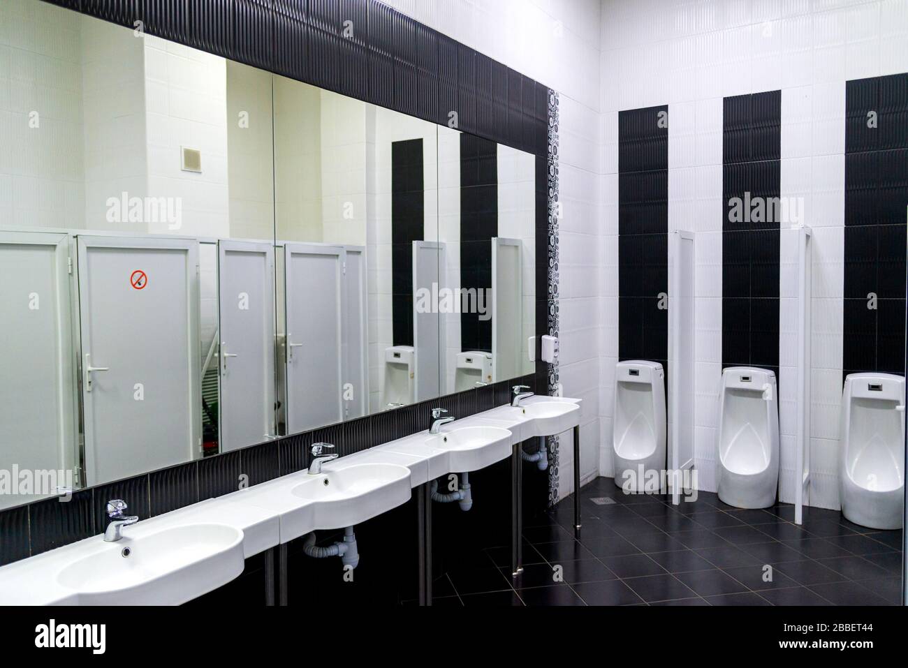 Public empty restroom with washstands, mirrors, toilets, urinals in ...