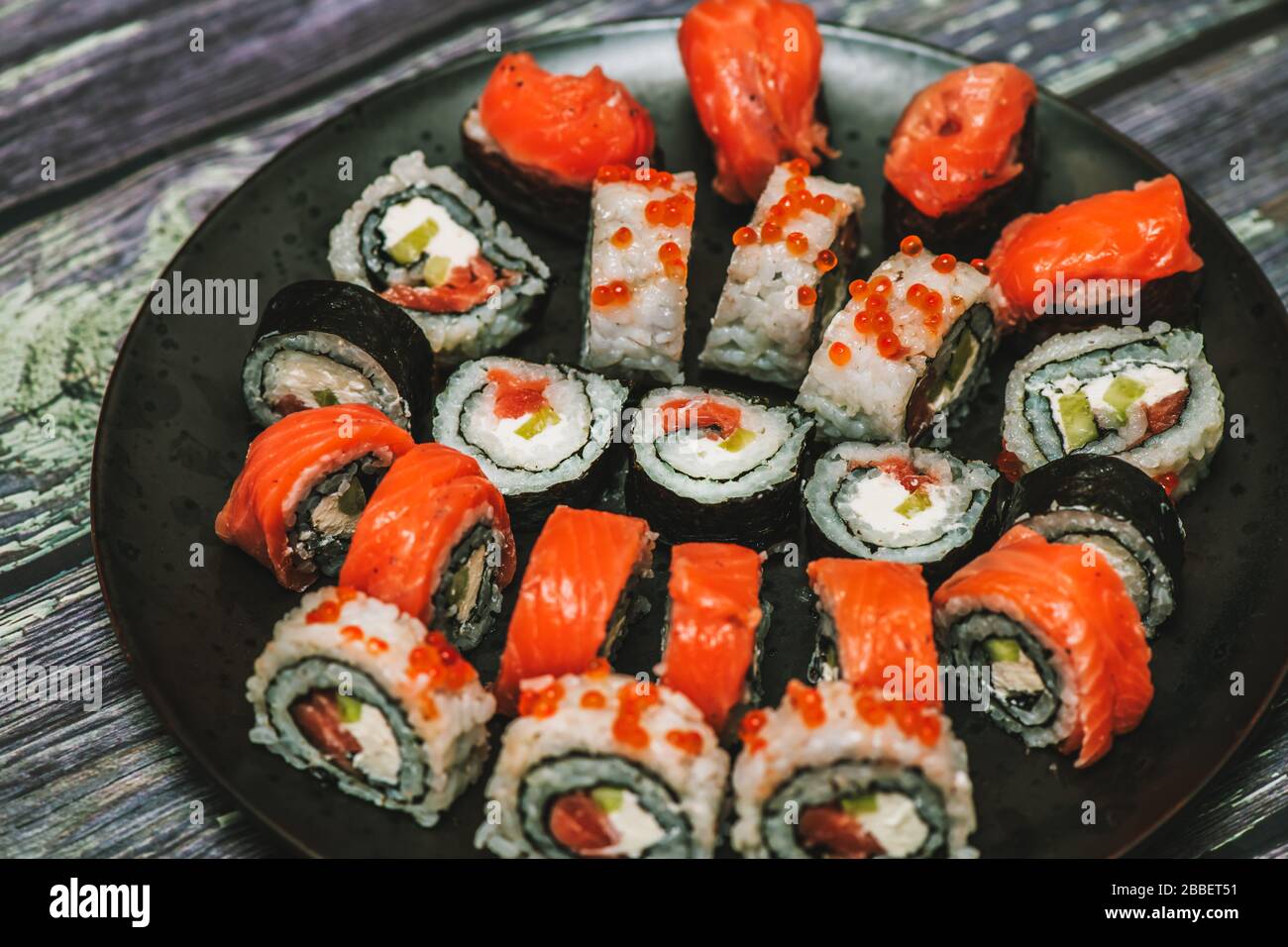 Assorted roll and sushi on a beautiful round plate or tray on a wooden ...