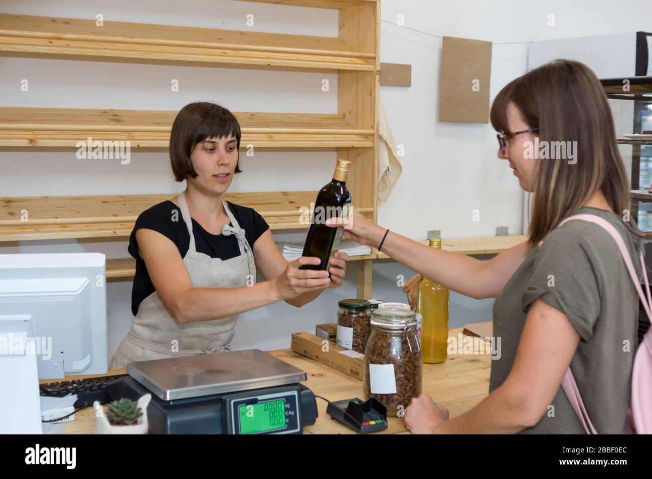 Female shop assistant serving a customer at a desk Stock Photo - Alamy
