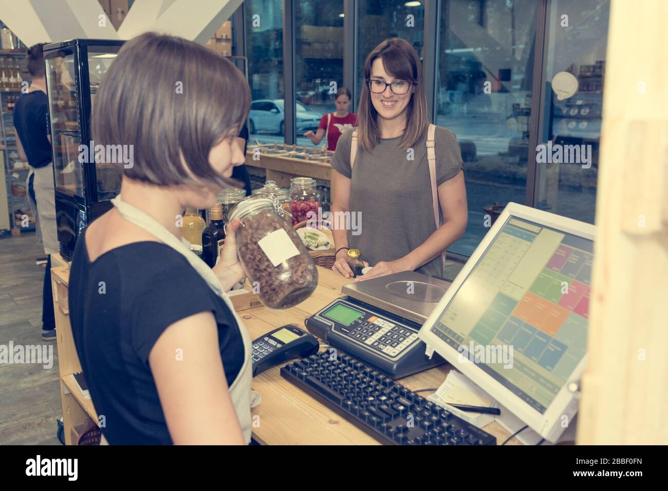 Female shop assistant serving a customer at a desk Stock Photo - Alamy