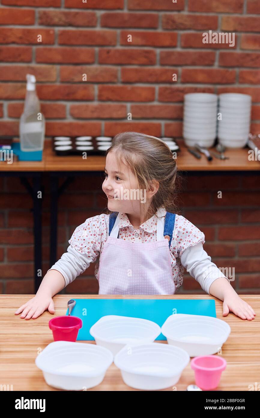 Little girl is ready for taking part in baking workshop. Baking classes ...