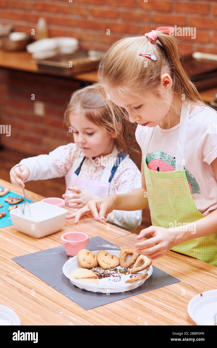 Little girls decorating baked cookies with colorful sprinkle and icing ...