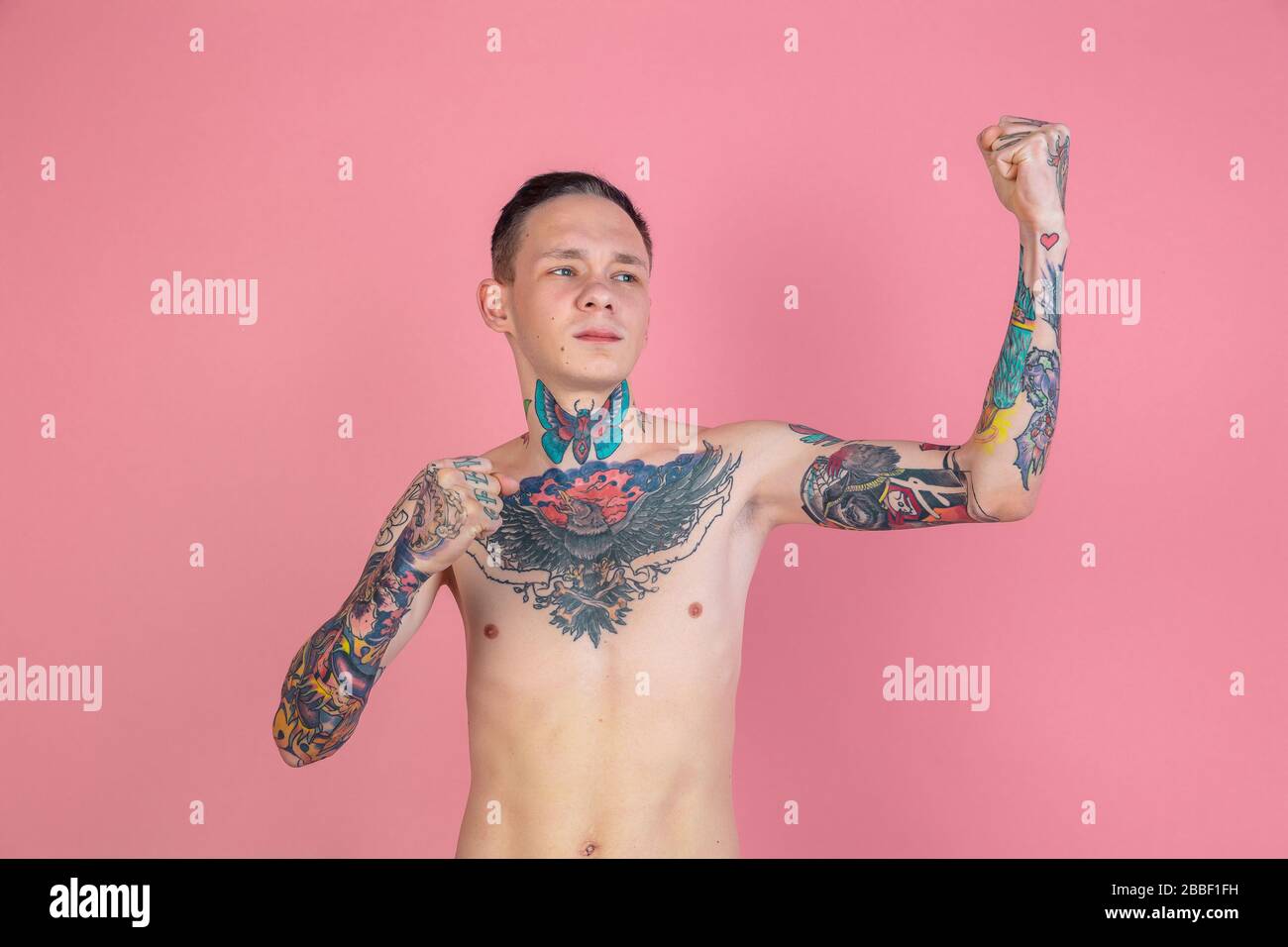 Strong gesture. Portrait of young man with freaky appearance on pink ...