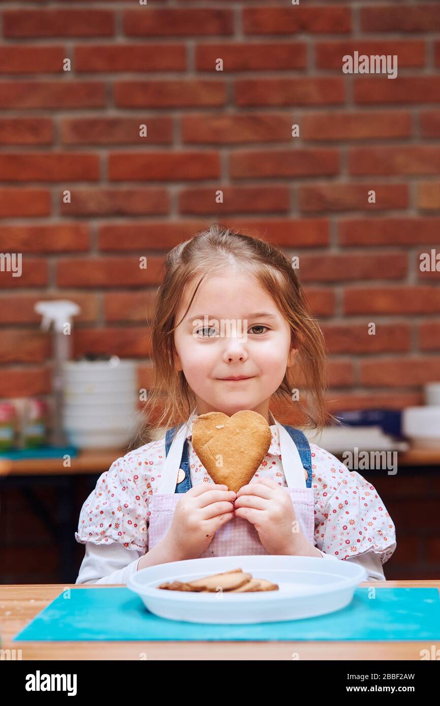 Little girl getting happy out of baked cookie made oneself. Kid taking ...