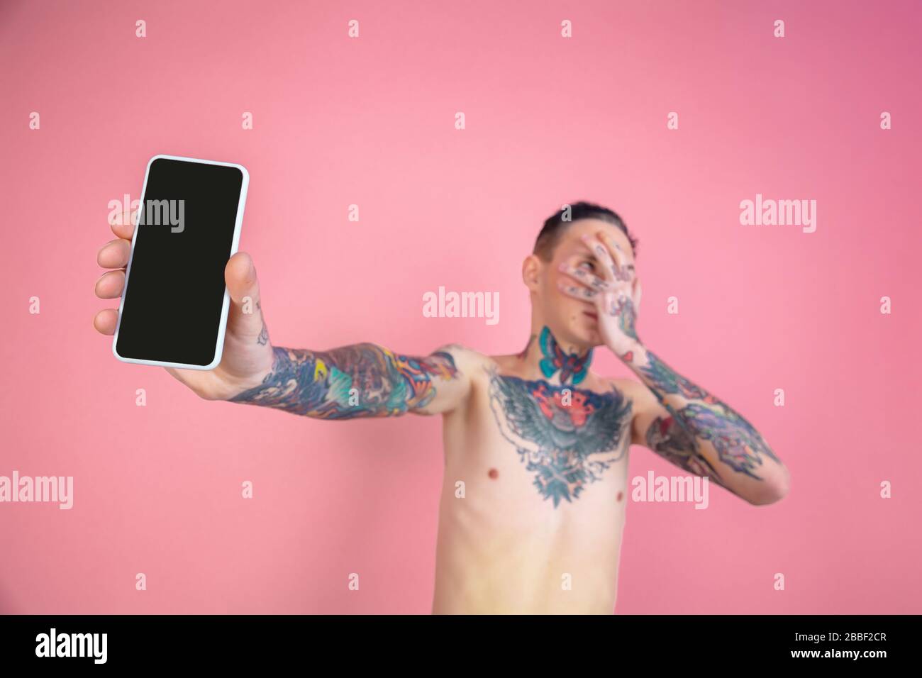 Showing blank phone screen. Portrait of young man with freaky ...