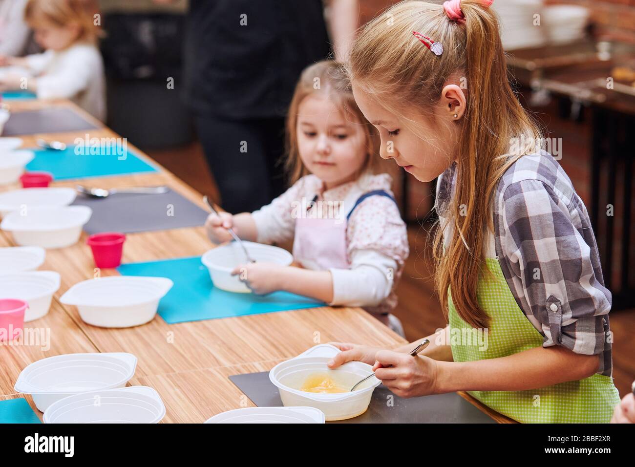 Little girls stirring the yolk with sugar. Kids taking part in baking ...