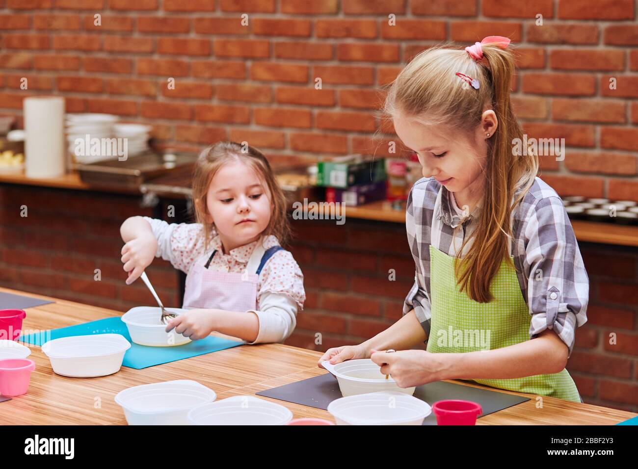 Little girls stirring the yolk with sugar. Kids taking part in baking ...