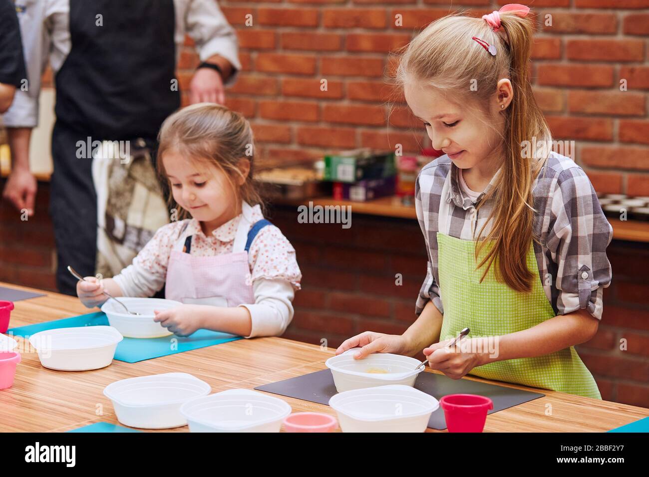 Little girls stirring the yolk with sugar. Kids taking part in baking ...