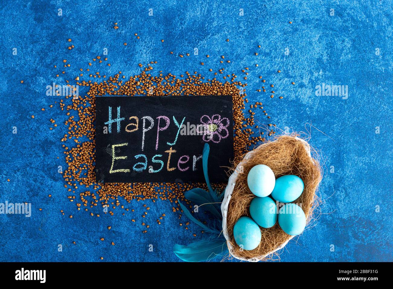 Blue easter eggs in nest next to blackboard with happy easter. Dark ...