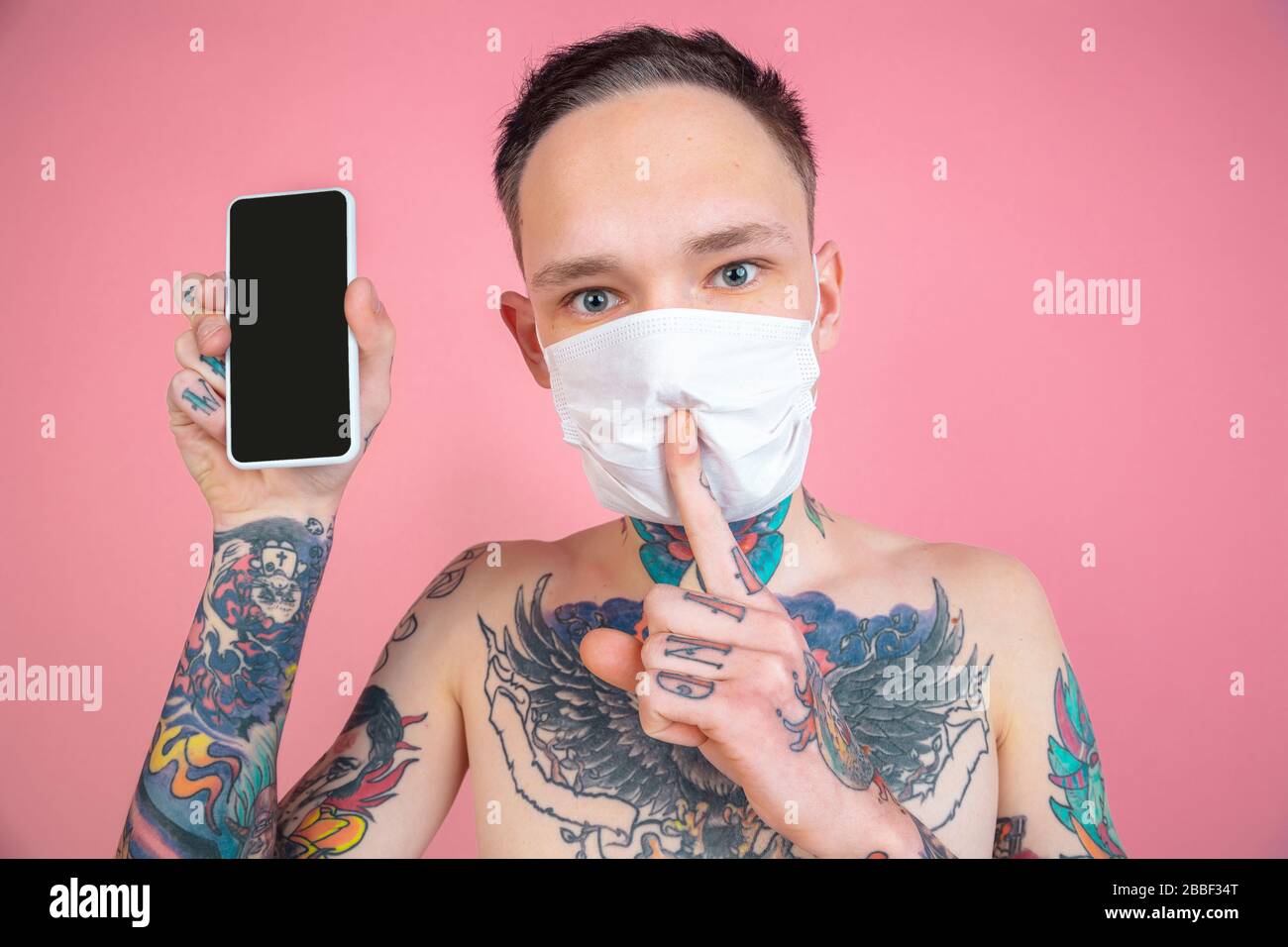 Blank phone's screen. Portrait of young freaky man on pink background ...