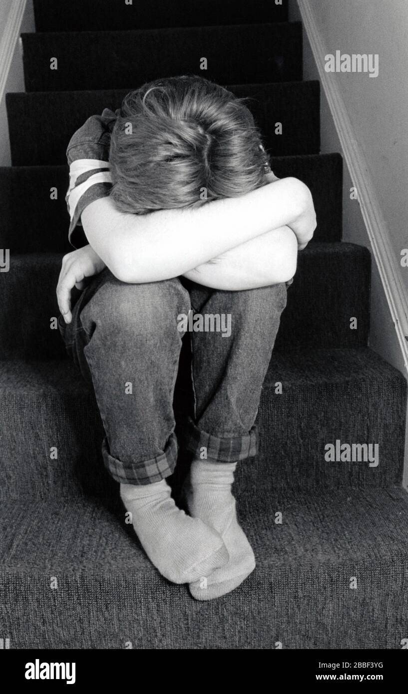 Boy sulking on the stairs. Posed by model UK 1989 Stock Photo - Alamy