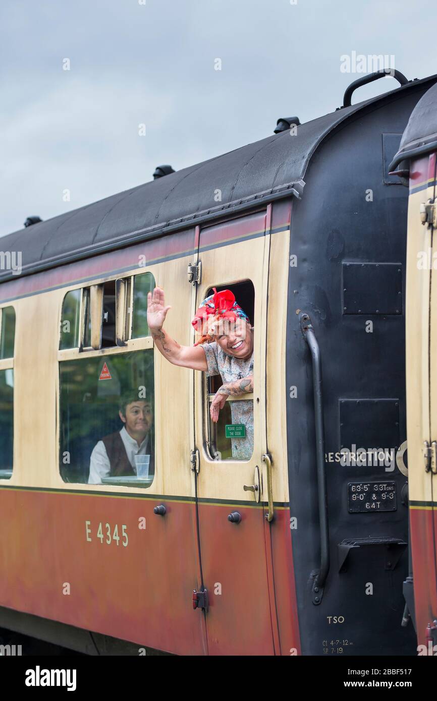 Smiling UK 1940s woman passenger leaning out of vintage railway ...