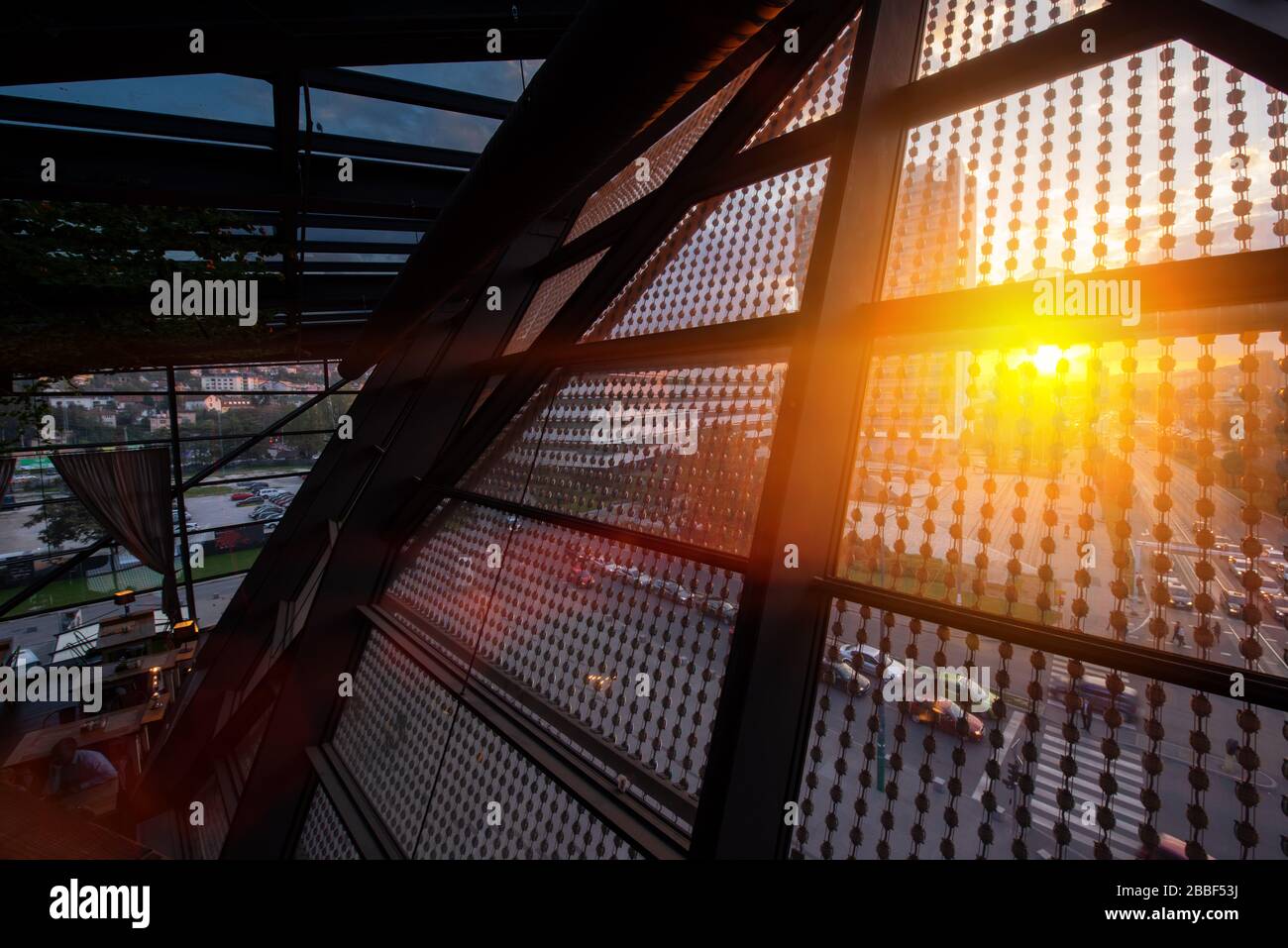sunset or sunrise above the city through a glass roof in a modern ...