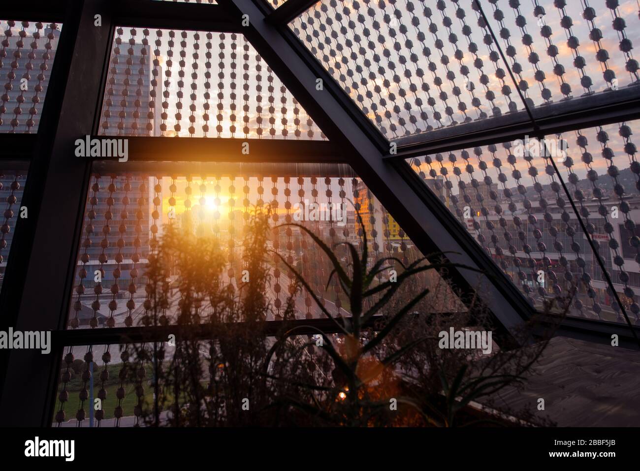 sunset or sunrise above the city through a glass roof in a modern ...