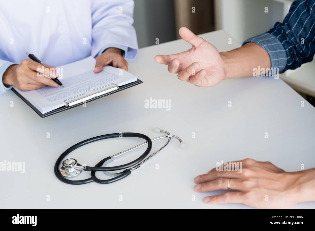 doctor working with patient taking notes with clipboard and discussing ...