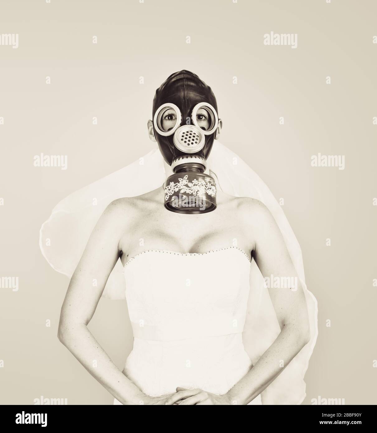 Beautiful young bride in a wedding dress and protactive gas mask on her ...
