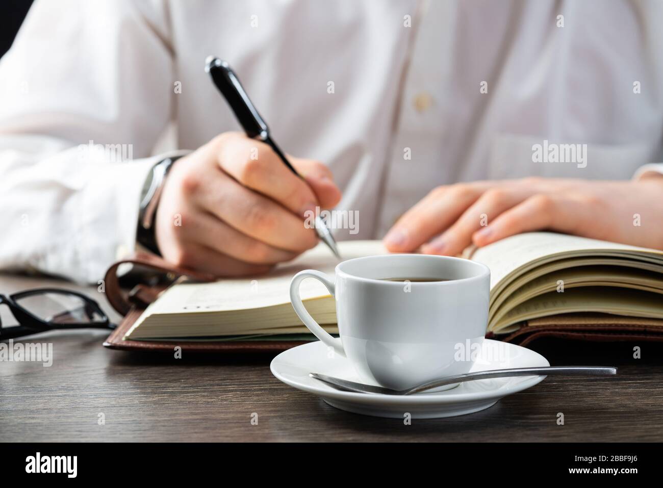 Man making notes with pen in notebook Stock Photo - Alamy