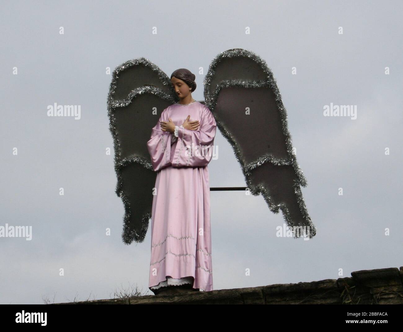 Angel statue on rooftop dressed in pink dress with wings decorated with ...