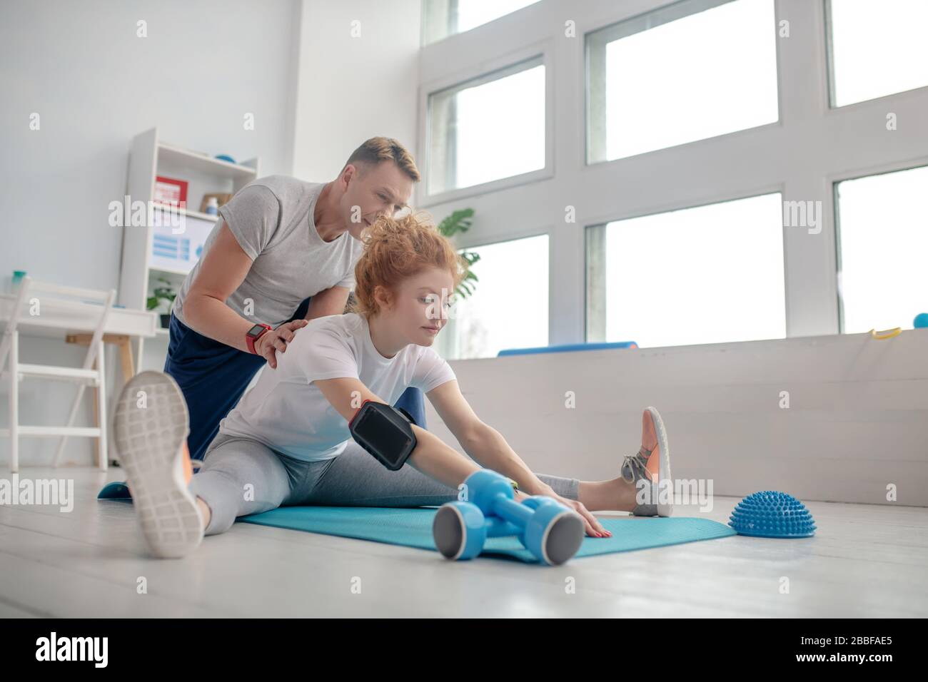 Female patient splitting on mat, male physiotherapist helping her Stock ...