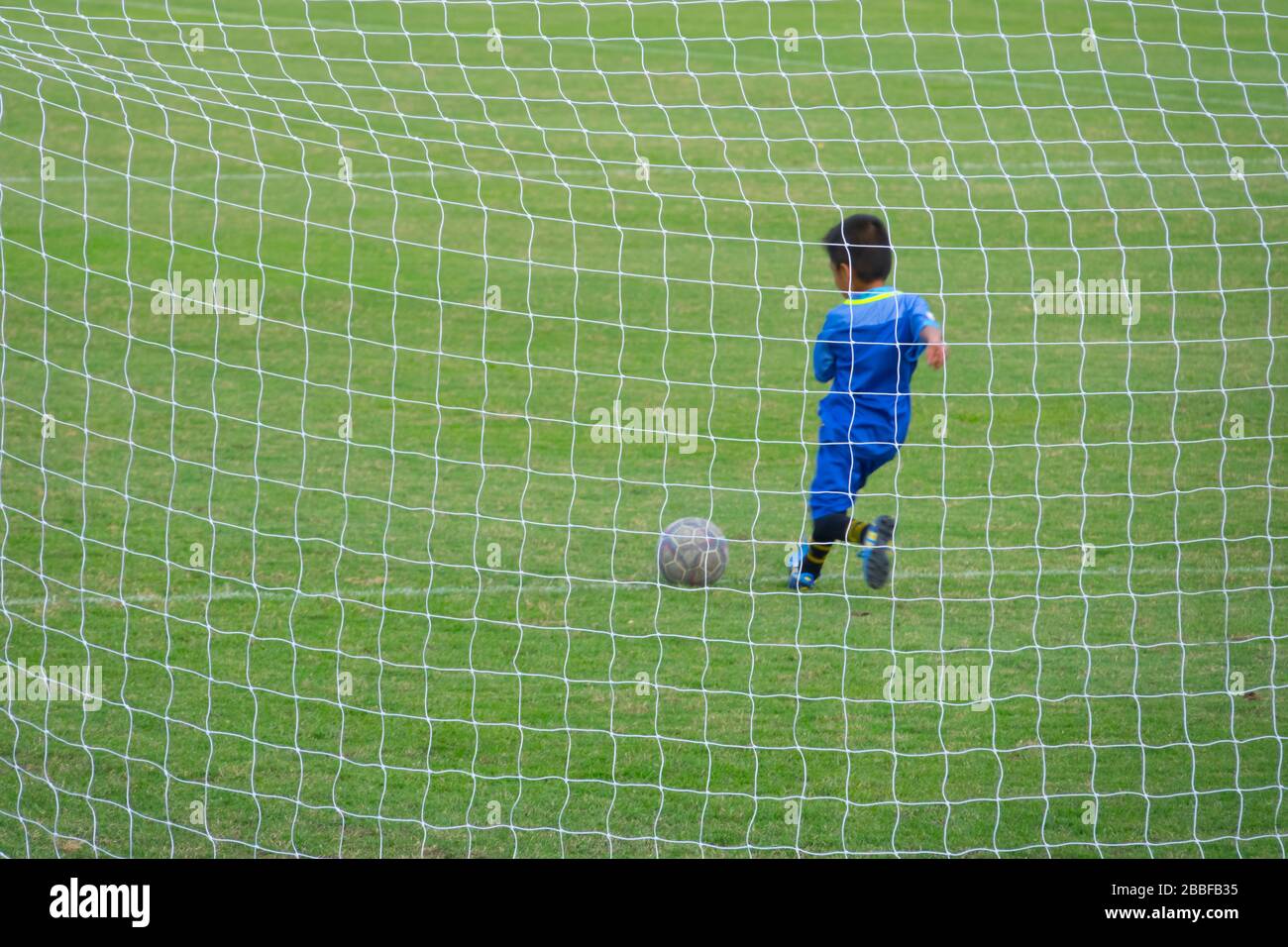 A net of goal in soccer field with a boy player shooting ball Stock ...