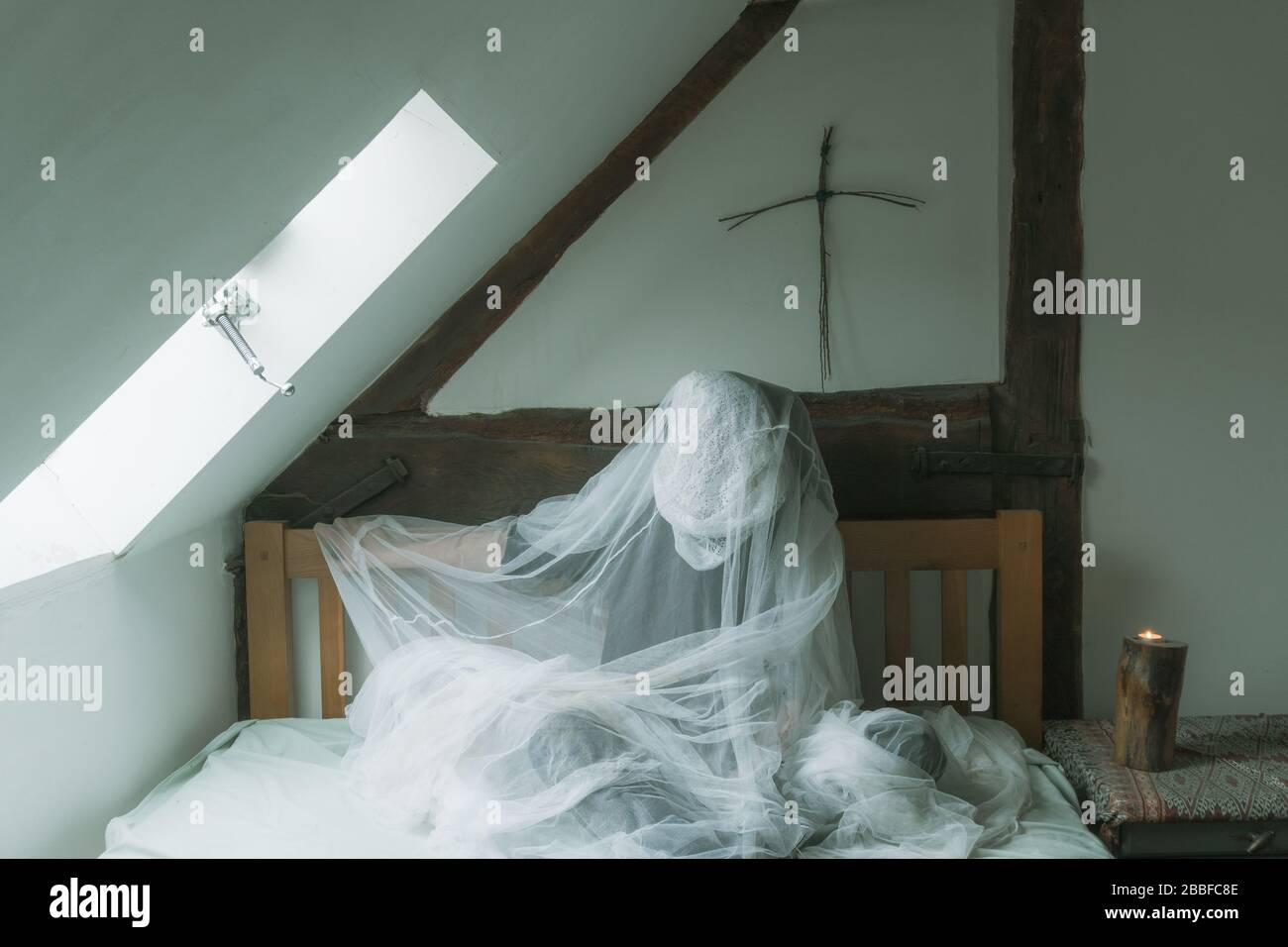 A spooky, ghostly figure sitting on a bed, covered in a sheet with a ...