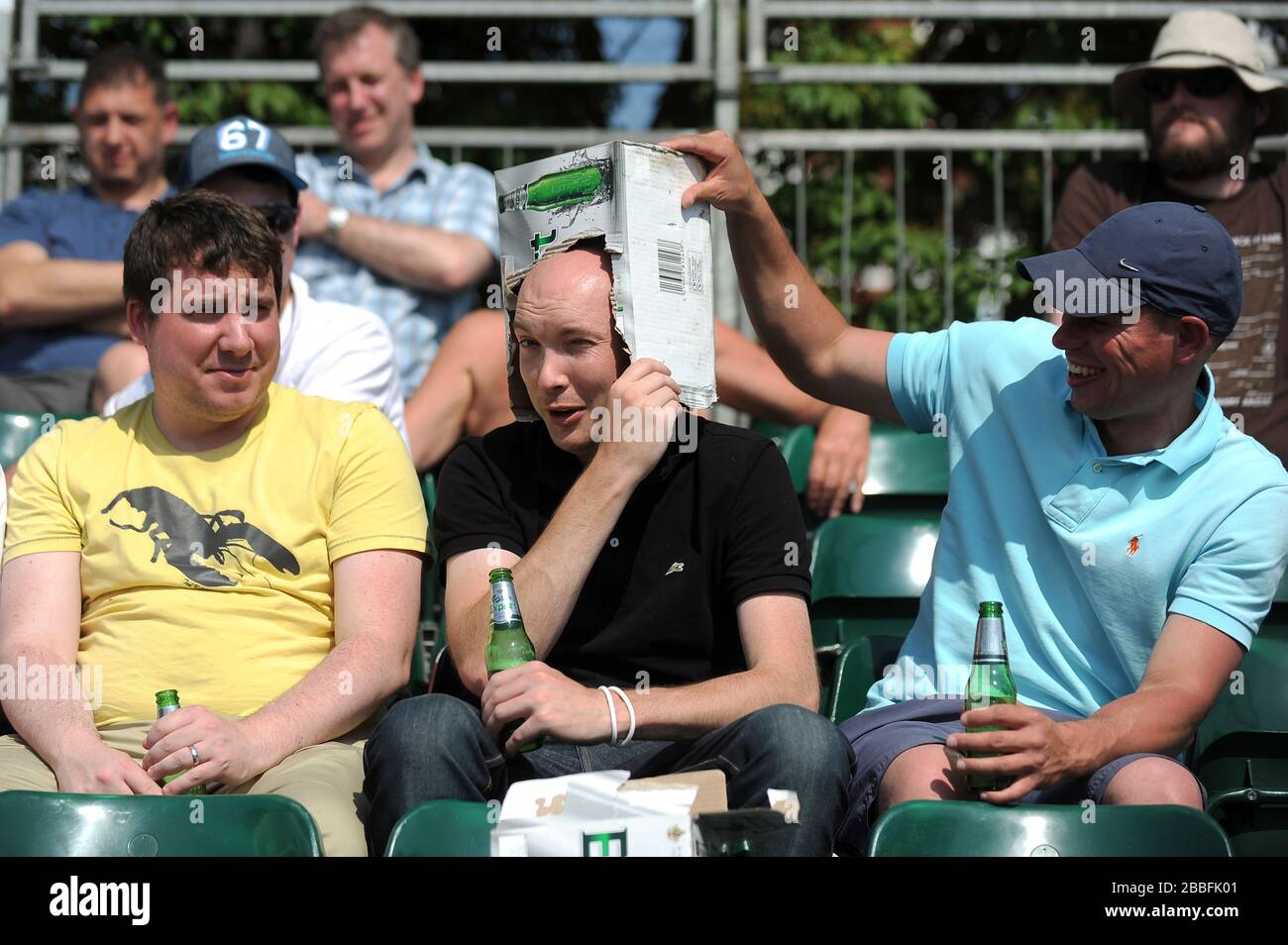 Fans in the stands shelter from the sun with a makeshift hat made from ...
