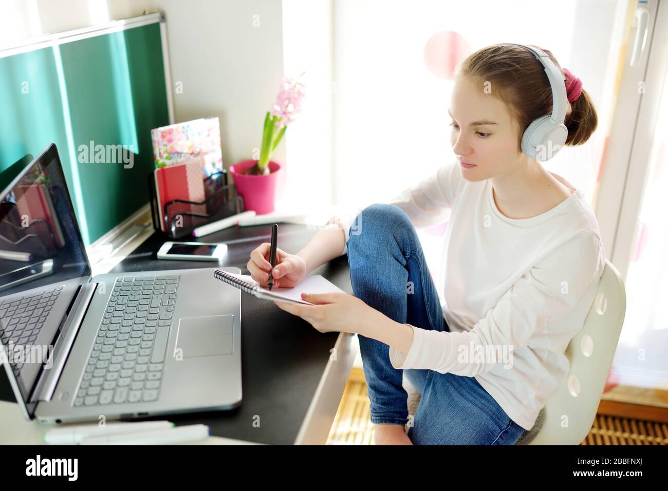 Preteen schoolgirl doing her homework with laptop computer at home ...