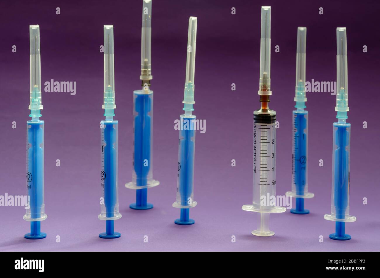 Group of used syringes on a lilac background. Seven different syringes ...