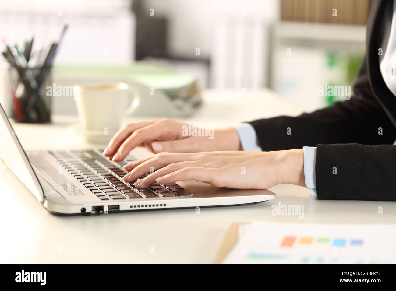 Close up of executive woman hands typing on laptop sitting on a desk at ...