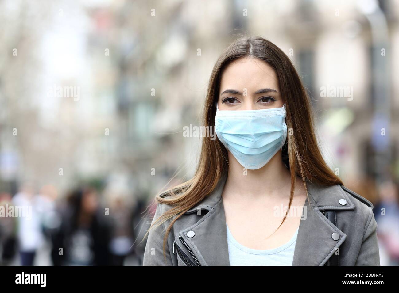 Front view portrait of a serious woman with protective mask looking ...