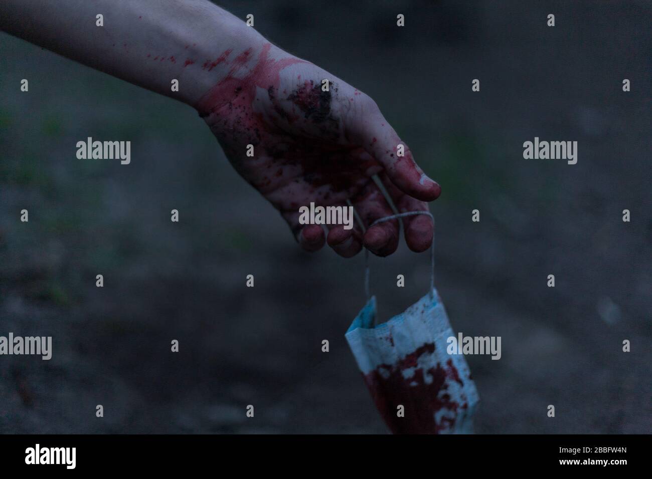 A medical bloodied mask lies on the ground with a bloody hand reaching ...