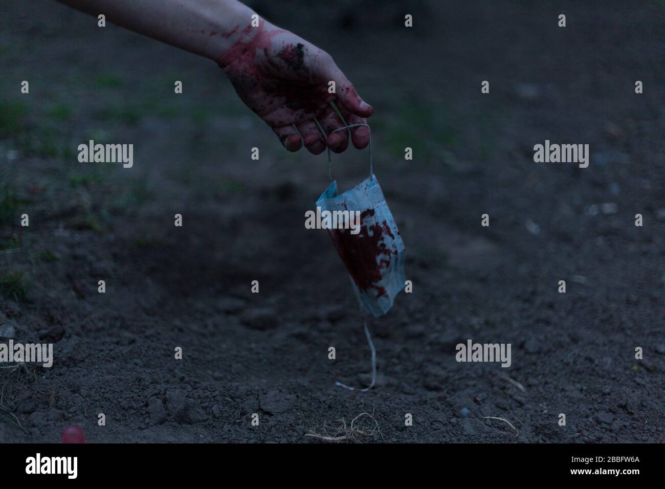 A medical bloodied mask lies on the ground with a bloody hand reaching ...